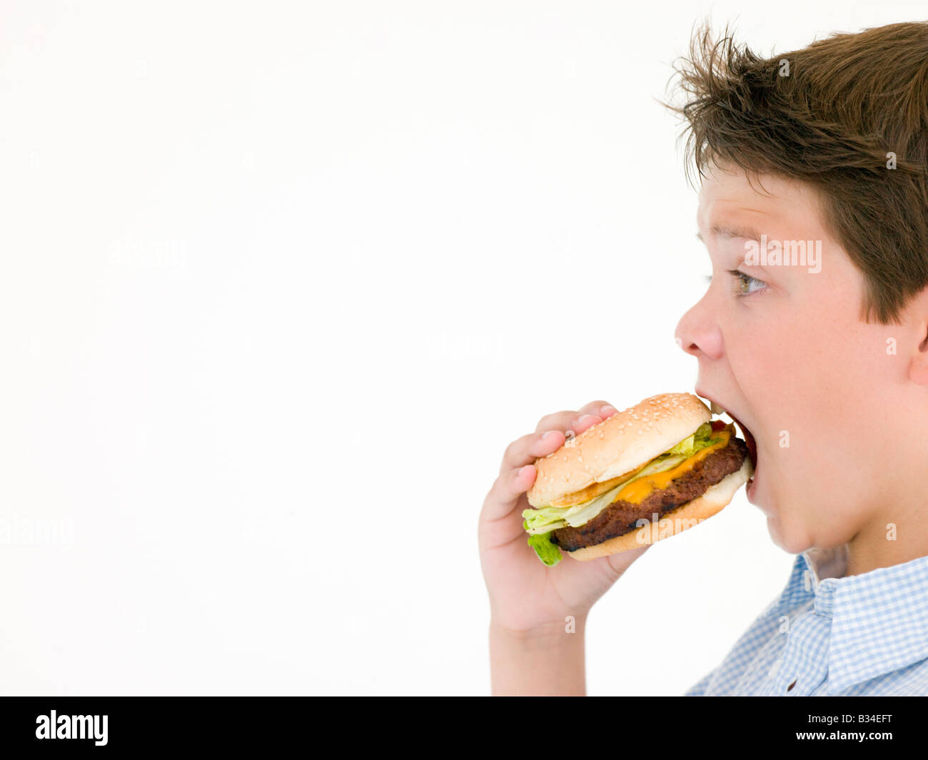 Young boy eating cheeseburger Stock Photo - Alamy