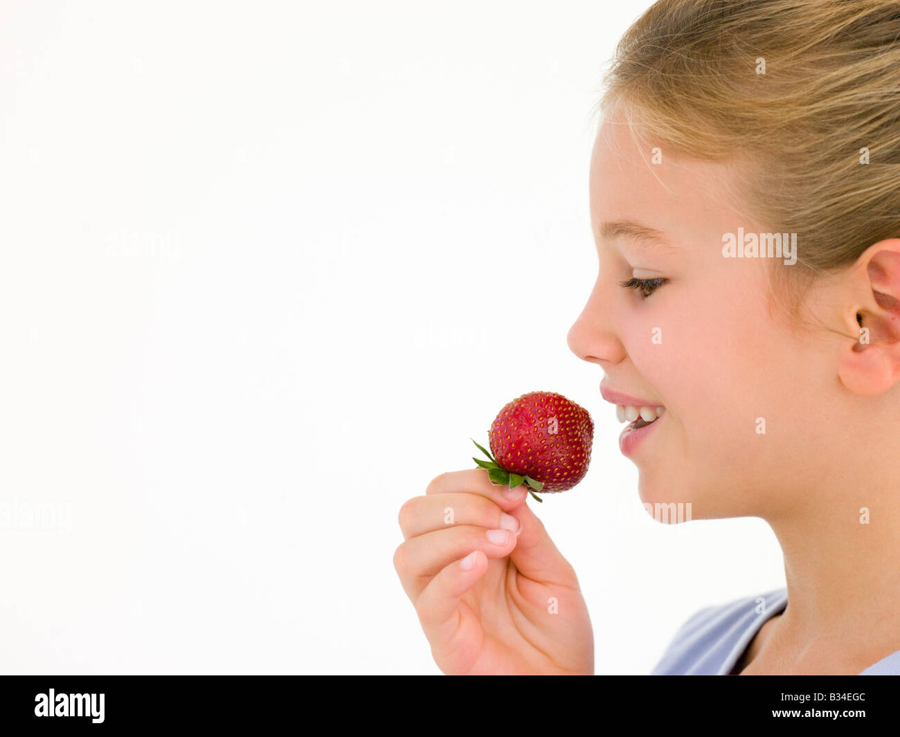 Young girl eating strawberry smiling Stock Photo - Alamy