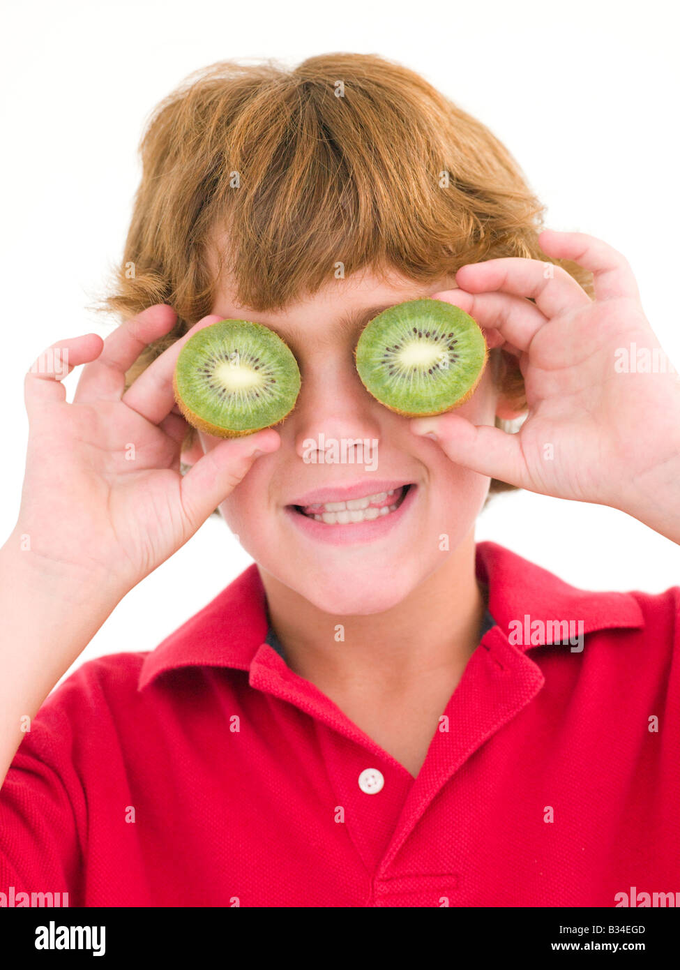 Young boy holding kiwi halves over eyes smiling Stock Photo - Alamy
