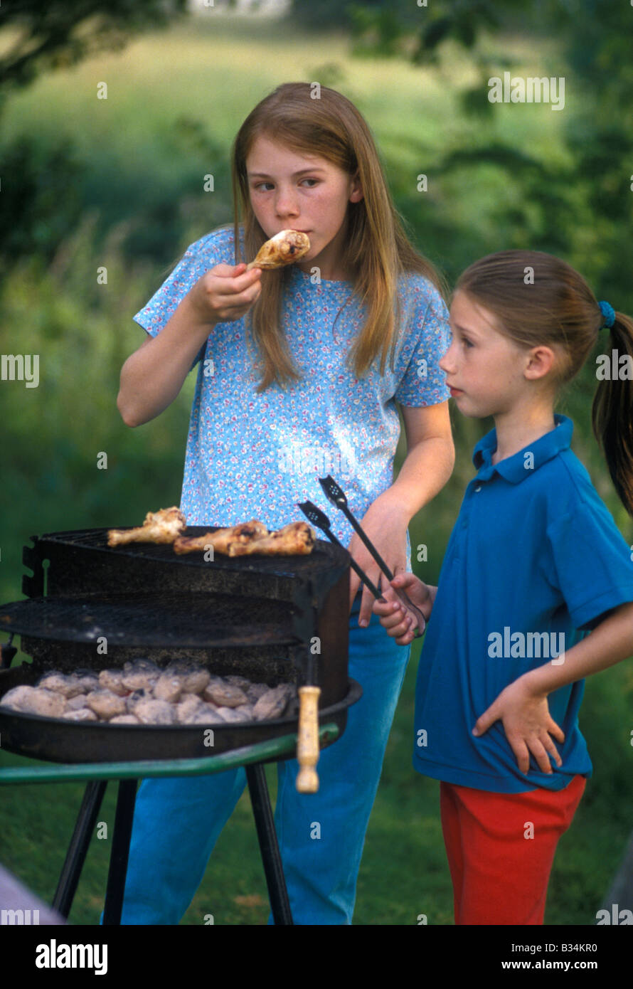 two girls barbecuing chicken in the garden with the chicken looking ...