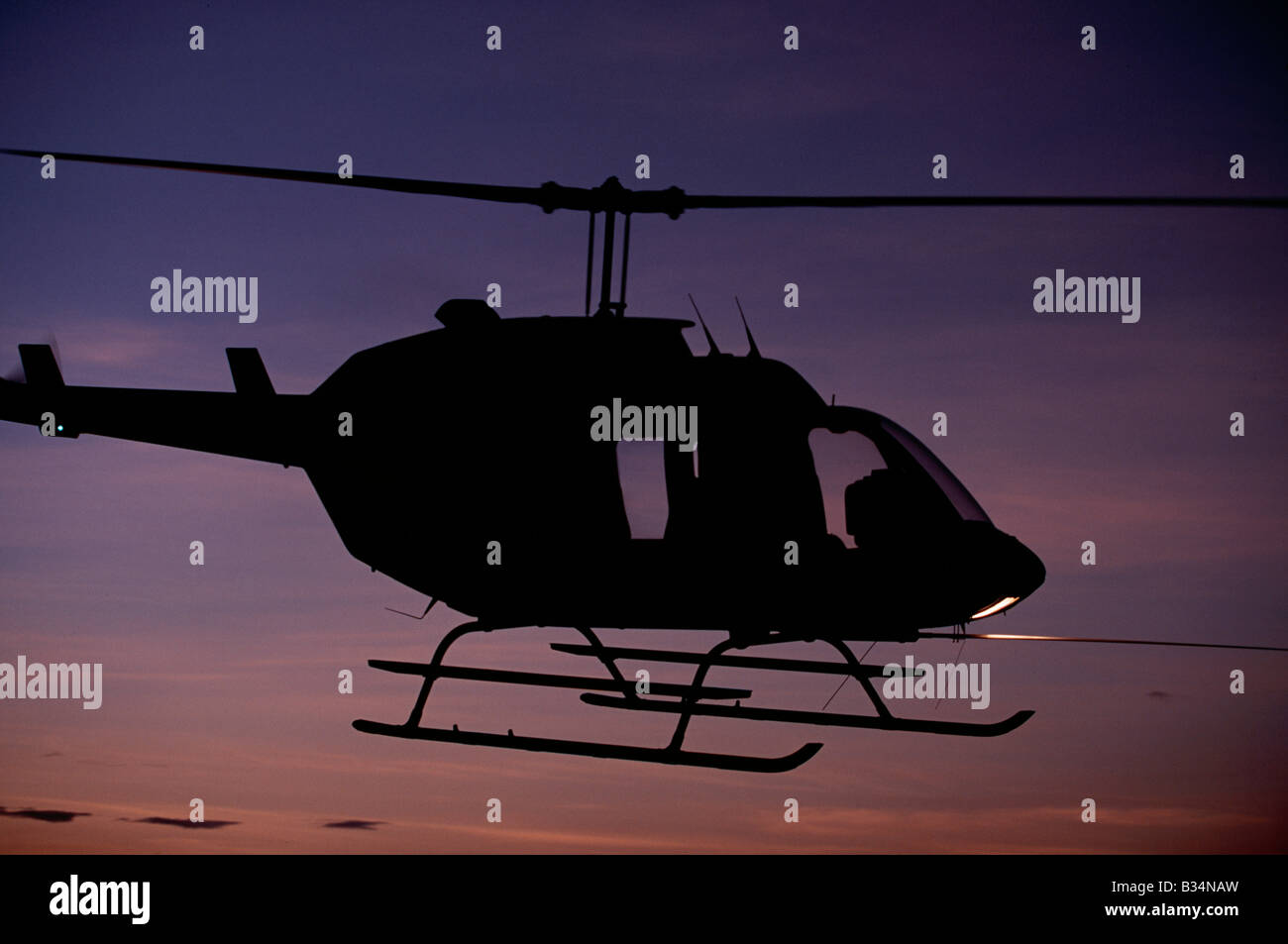 Kenya, Lake Turkana. A Bell Long Ranger helicopter hovering at sunset ...