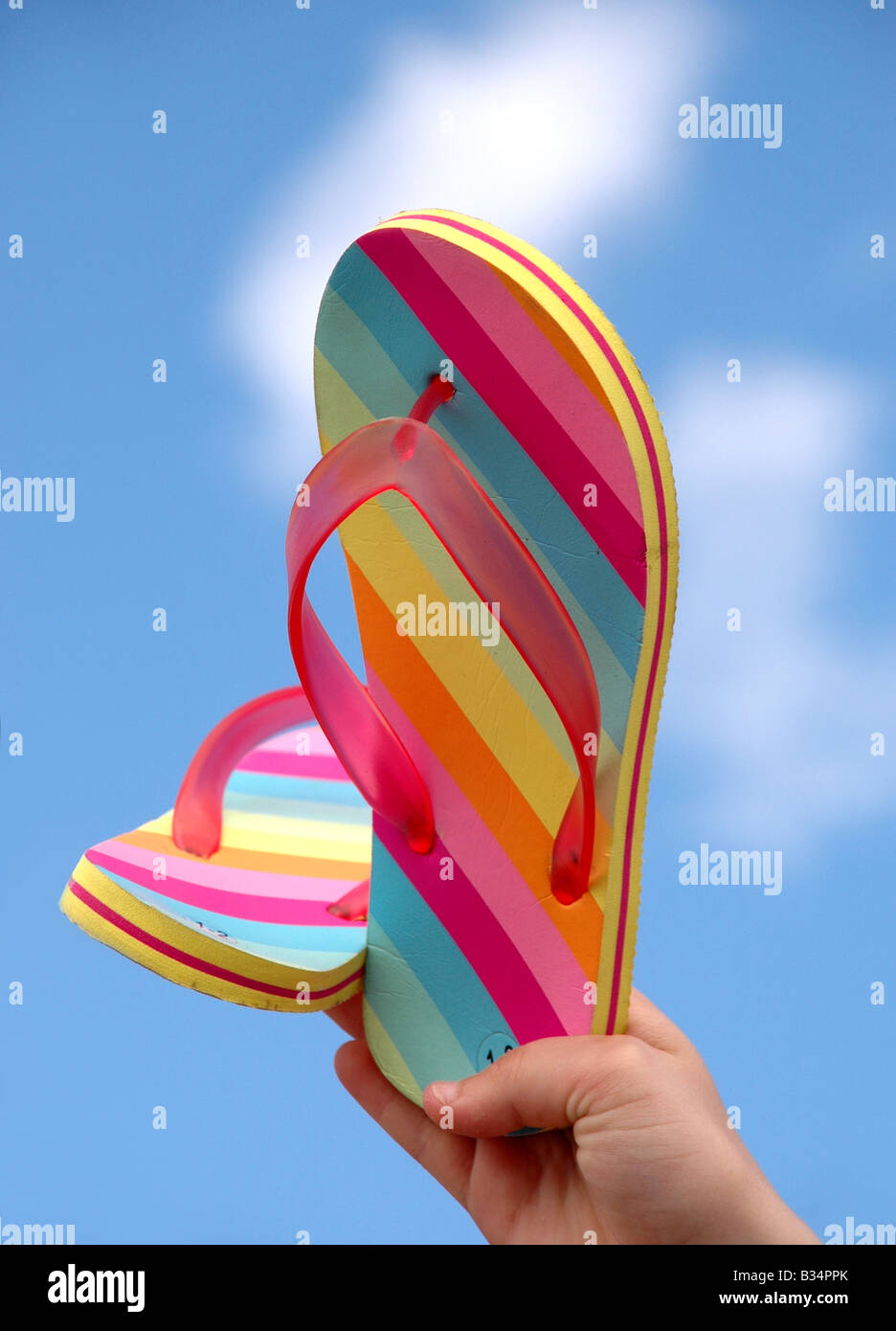 A teenage girl holds up a pair of striped and colourful flip flops ...