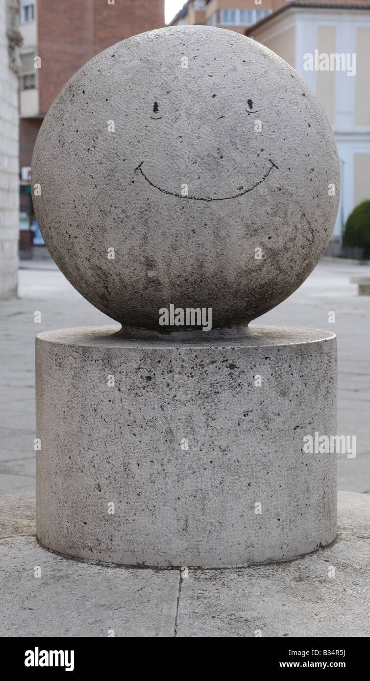 Round spherical stone bollard street furniture with smiling graffiti in ...