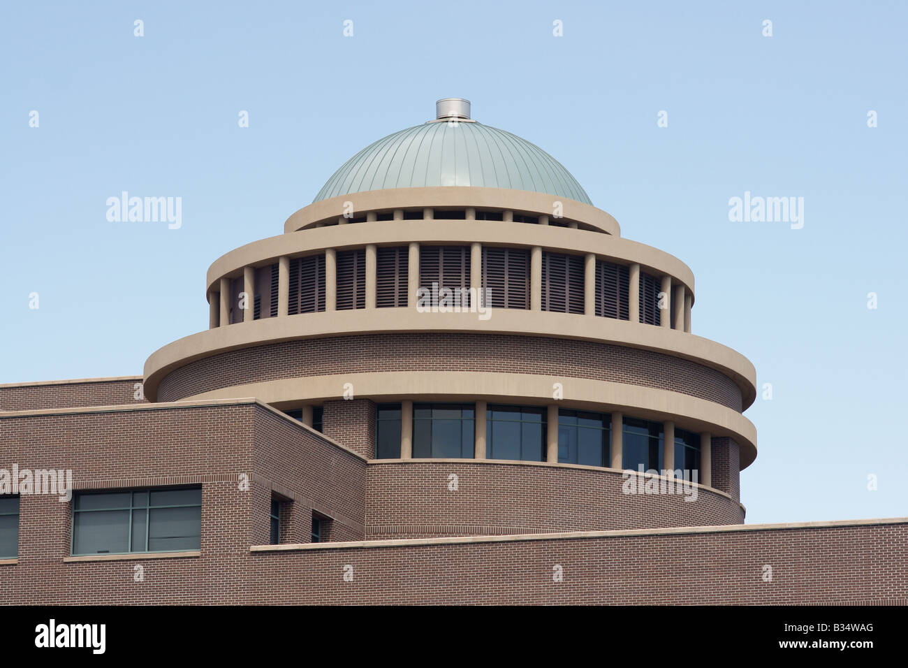 A light blue rotunda on top of a brick building in front of a clear sky ...