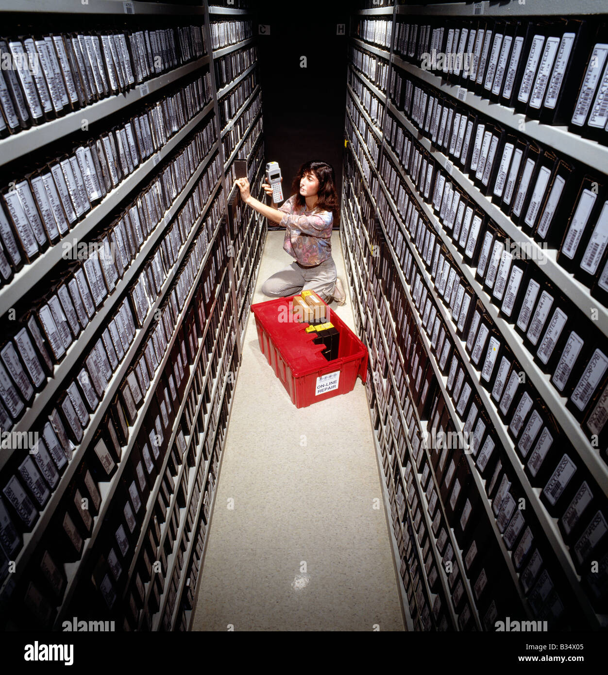 Woman checks back-up library of computer data on tapes using a handheld ...