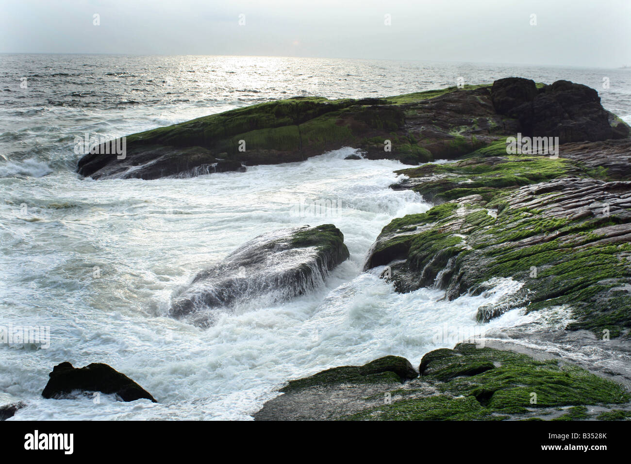 Surf splashes over beach rocks Stock Photo - Alamy