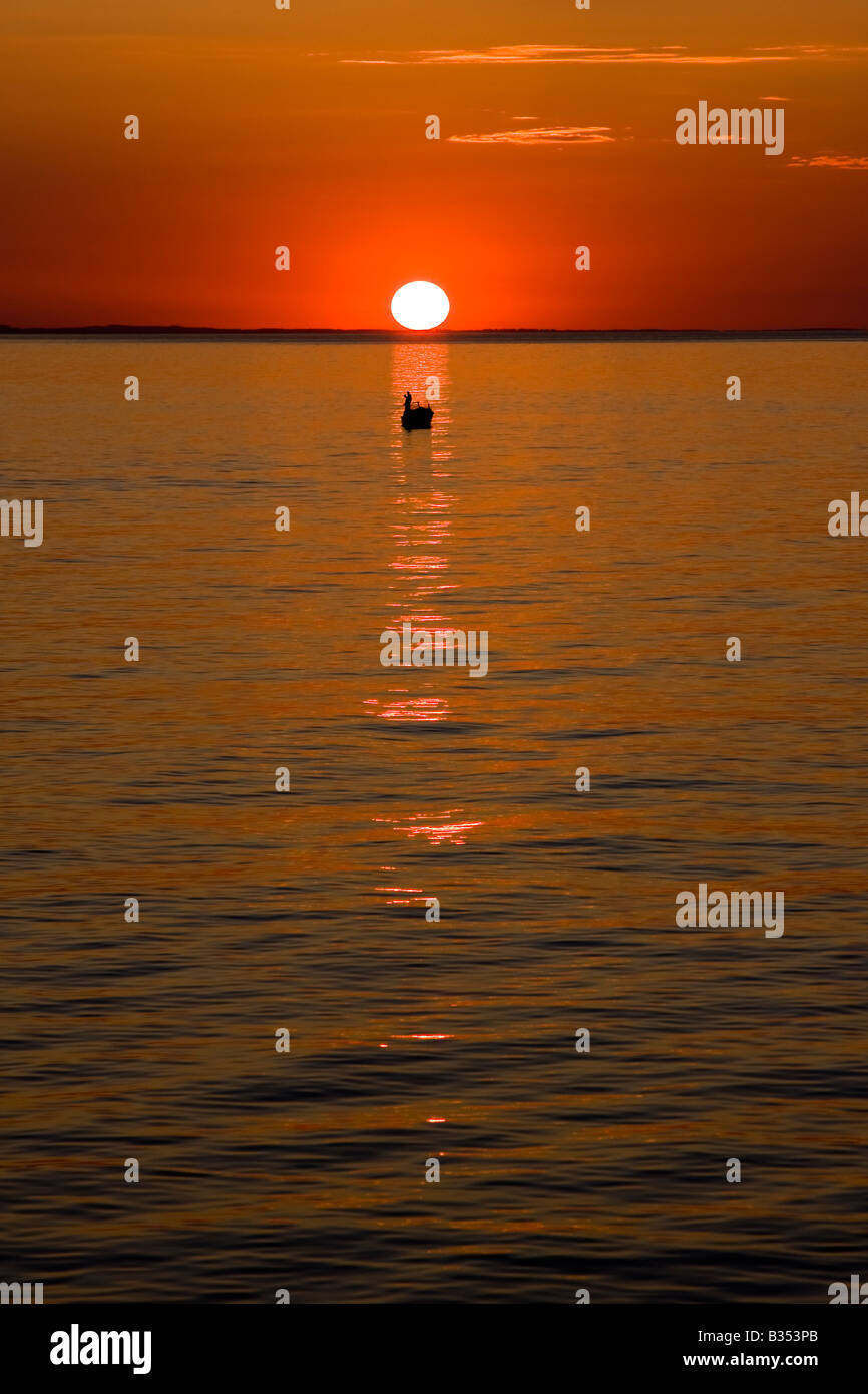 fisherboat in an orange sunset Stock Photo - Alamy