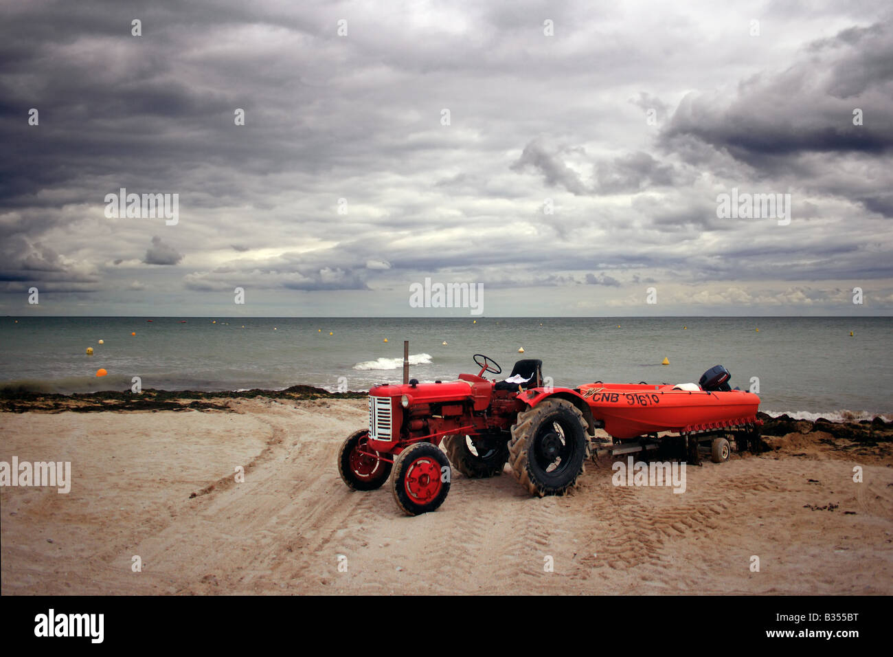 A tractor towing an inflatable boat on the sand beach of Langrune sur ...