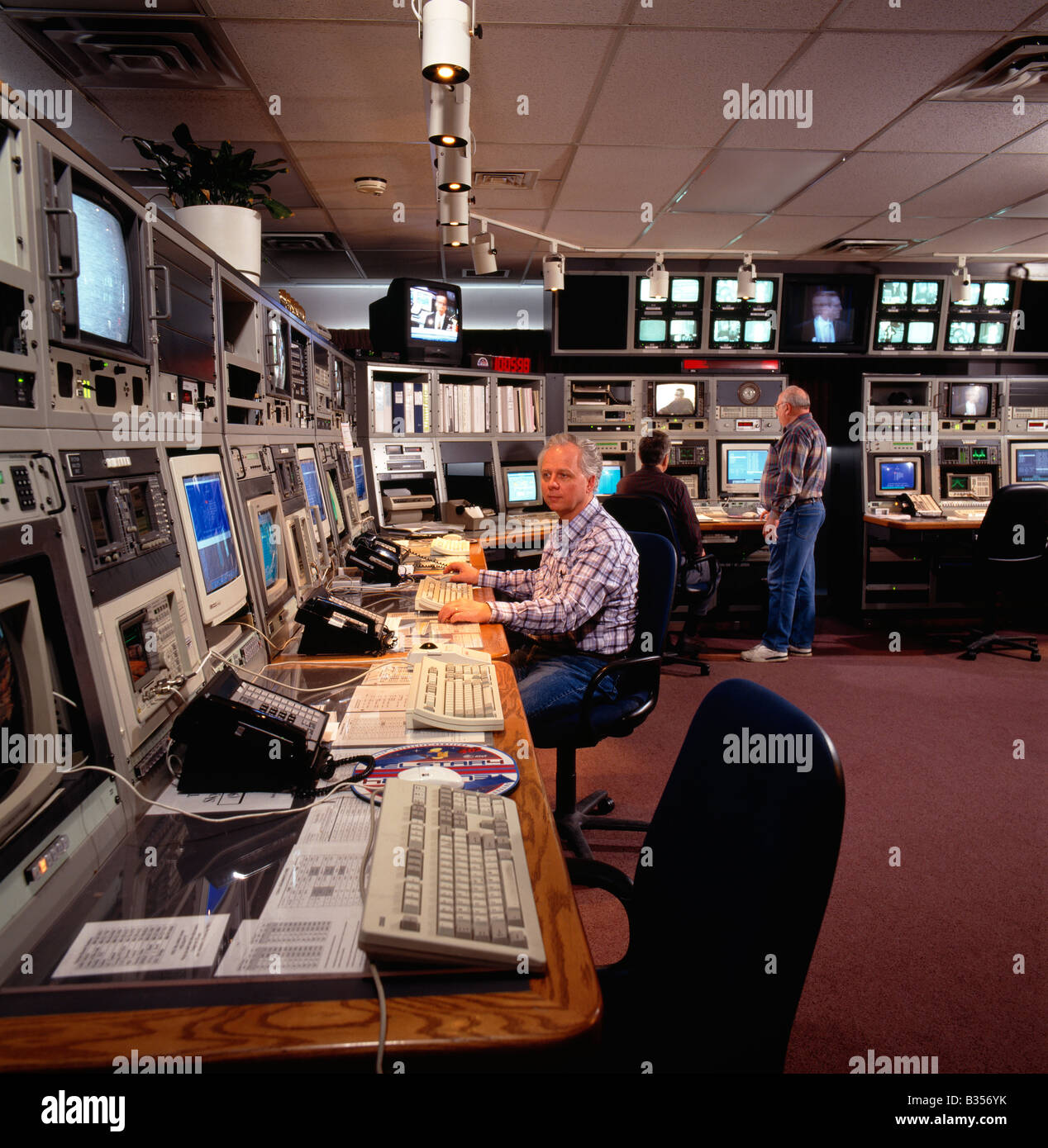 Men working at computer console in high tech telecommunications ...