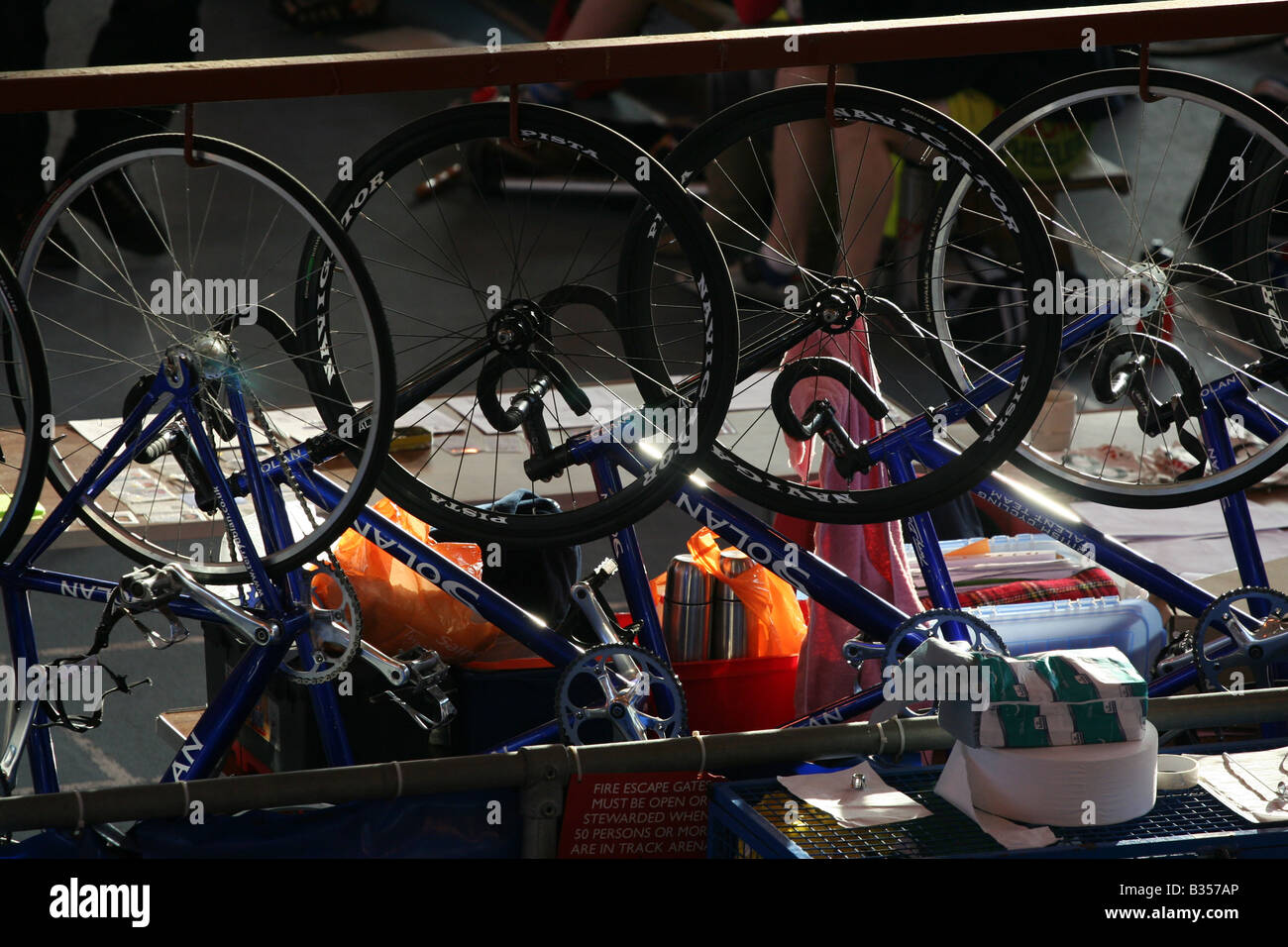 Matching dark blue track racing bicycles hanging by their front wheels ...