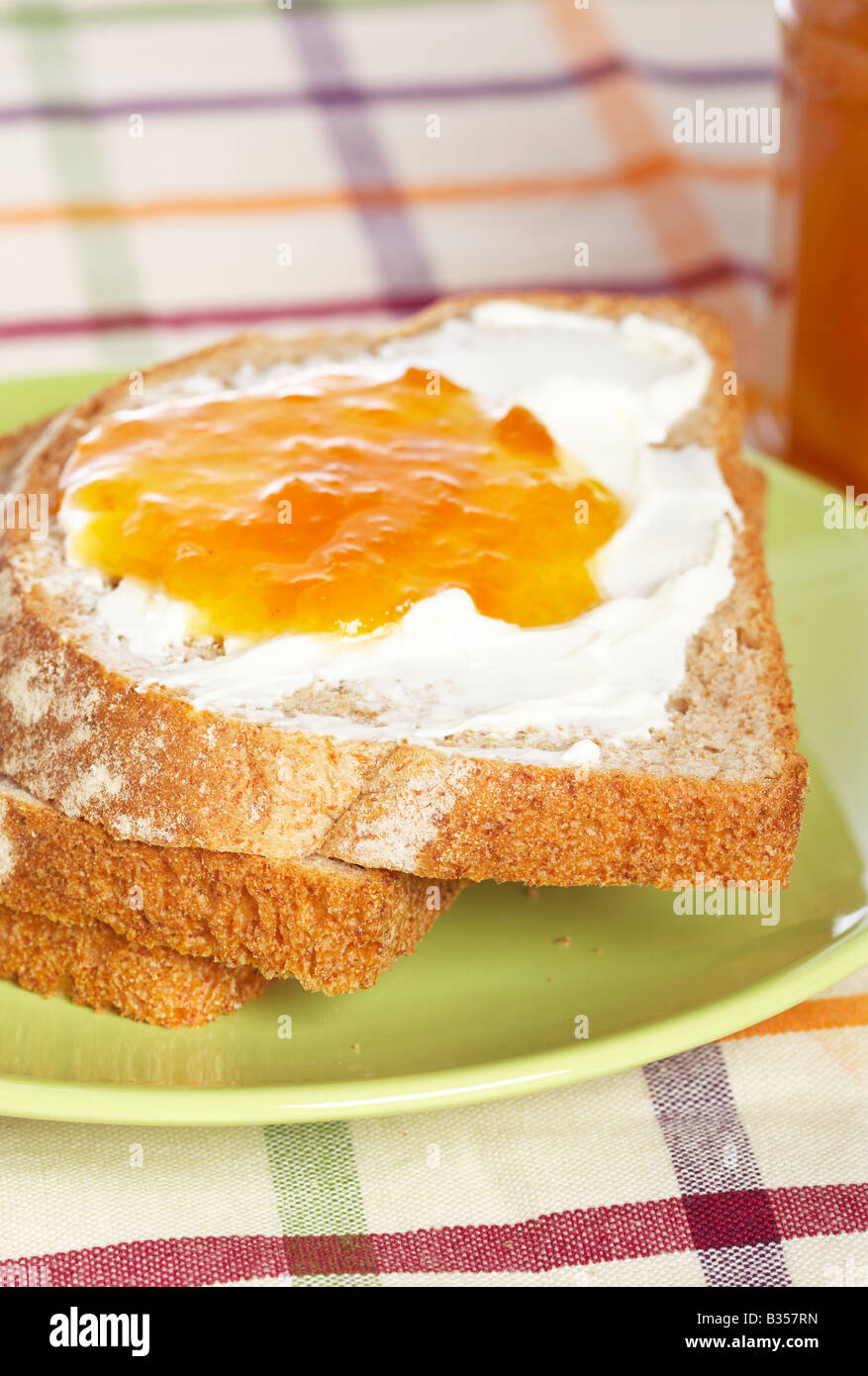 Toast with butter and peach jam glass jar in the green plate with soft ...