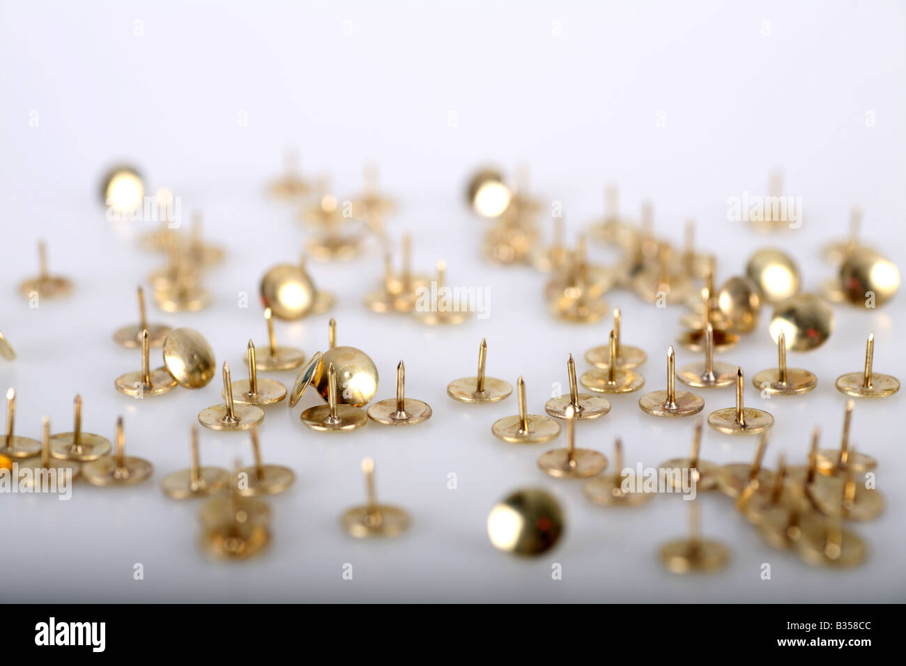 Upturned brass drawing pins on a white background Stock Photo - Alamy