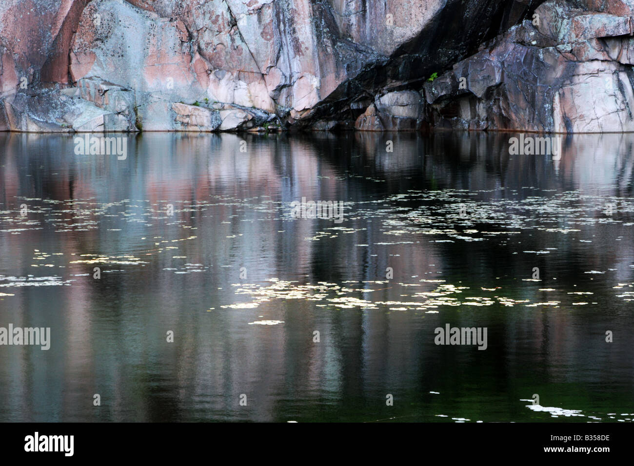 Beautiful reflections of granite rock cliff on George Lake Killarney ...