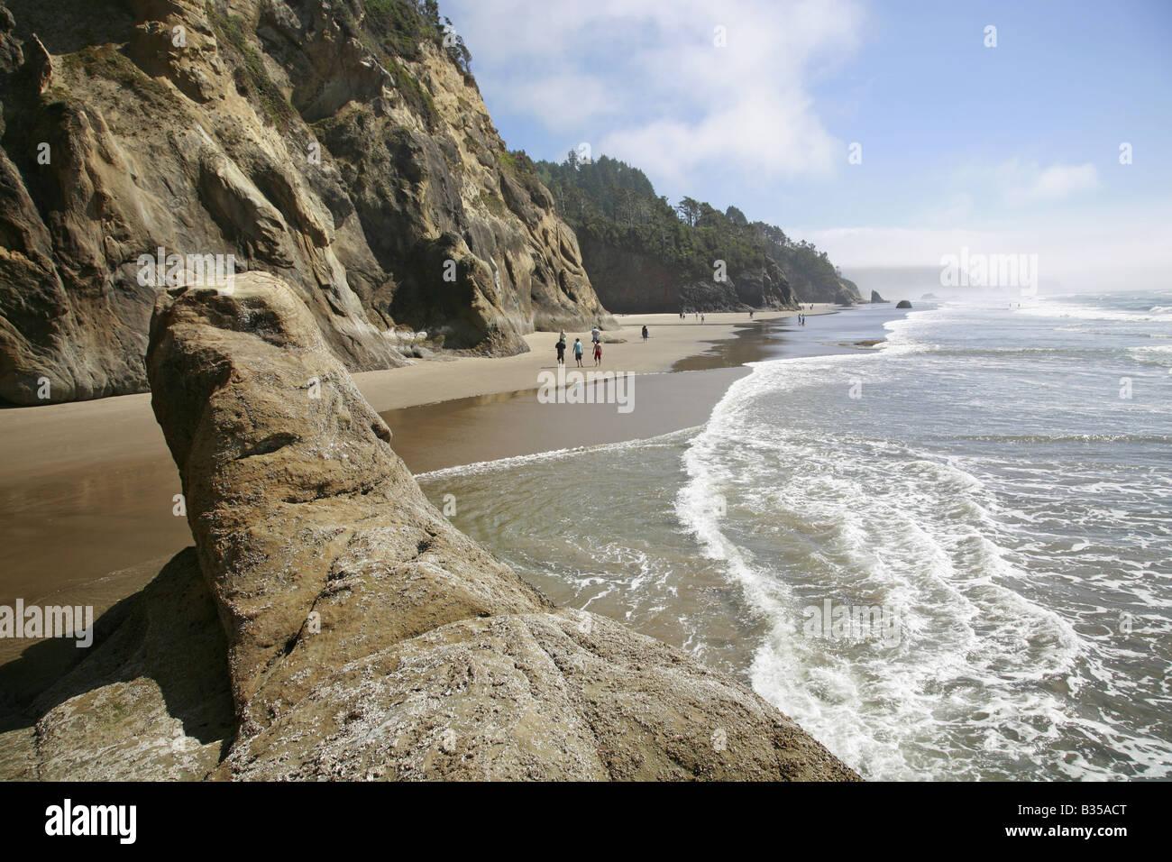 Visitors walk along the beautiful beach at Hug Point State Park near ...