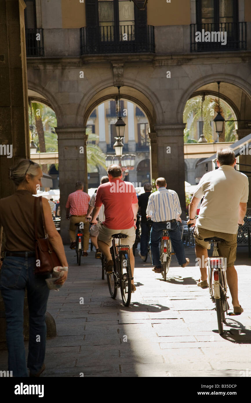 SPAIN Barcelona Group of men ride bicycles through plaza passers by ...