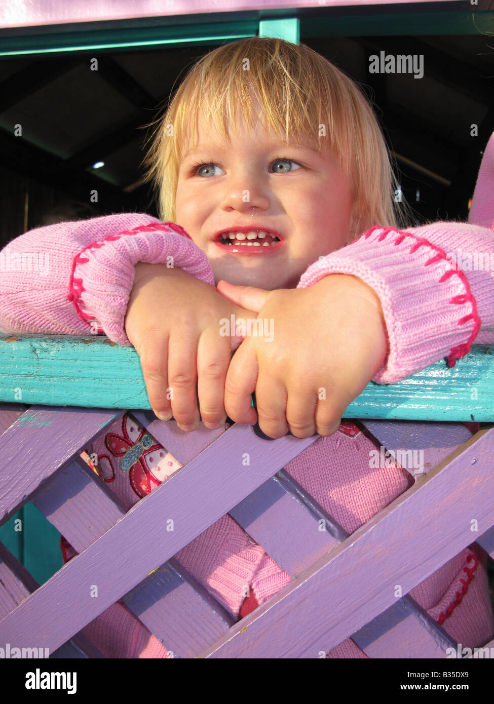 Young child girl leaning over fence Stock Photo - Alamy