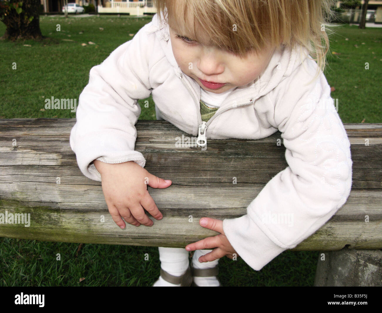 Child girl leaning on a log Stock Photo - Alamy