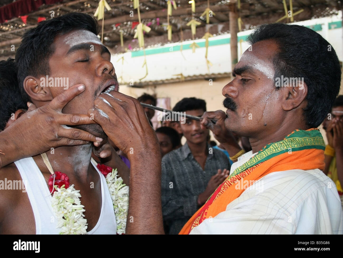 Hindu priest pierces a large spear through a devotees cheeks in a form ...