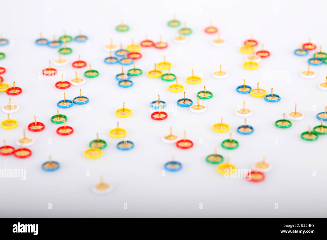 Upturned brass drawing pins with colored thumbnail on a white ...