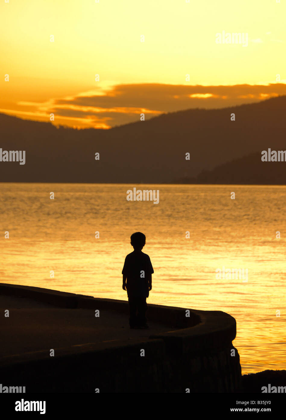Silhouette of a young boy looking towards the sunset Stock Photo - Alamy
