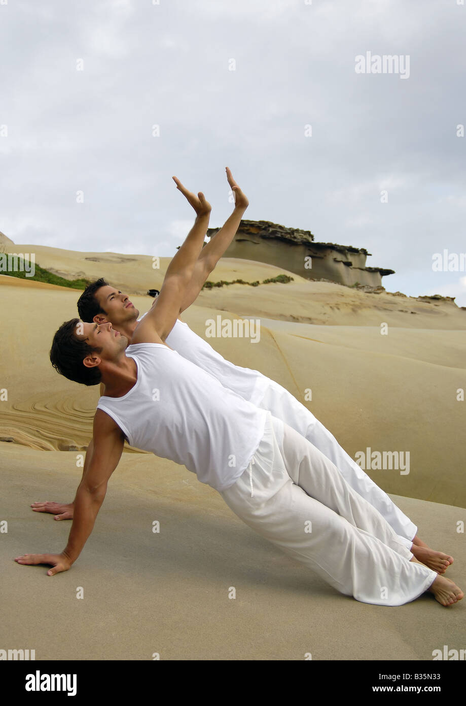 Two young men practicing yoga Stock Photo - Alamy