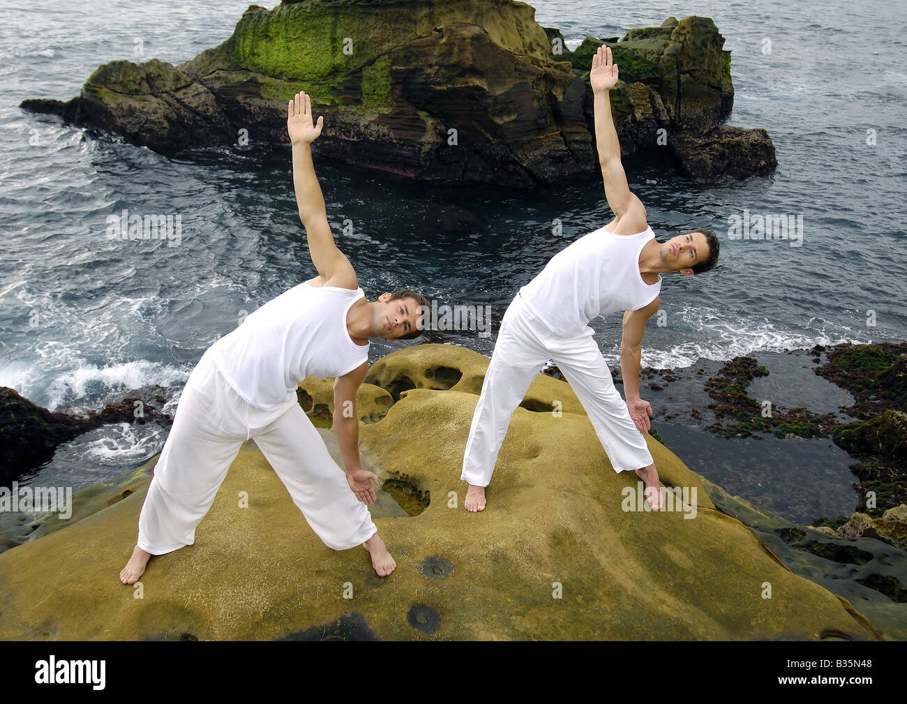 Two young men practicing yoga Stock Photo - Alamy