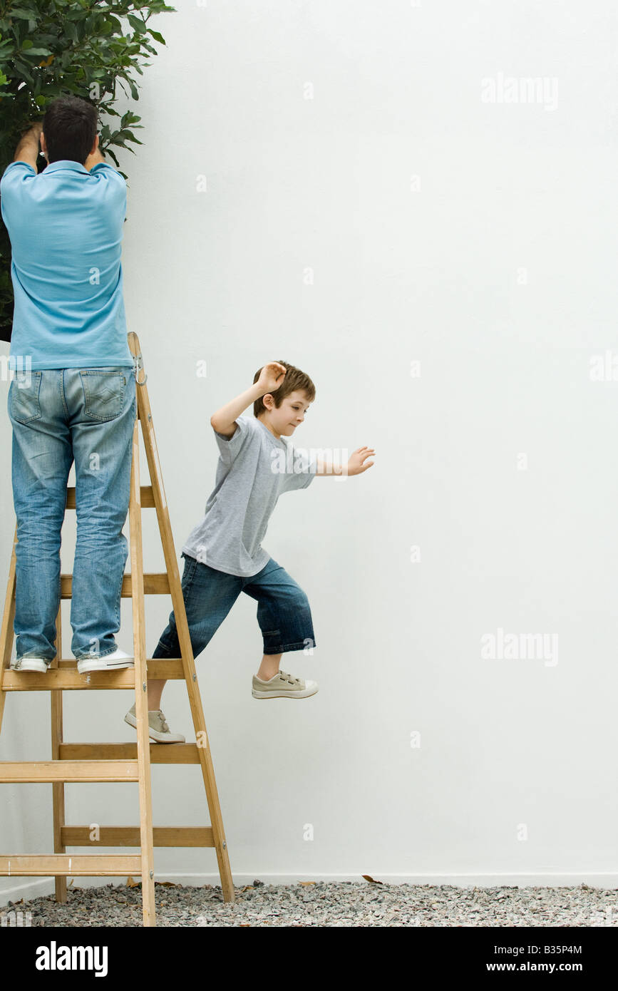 Father and son standing on ladder, boy leaping off Stock Photo - Alamy