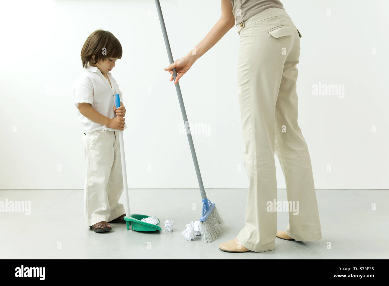 Little boy helping his mother sweep the floor, cropped view Stock Photo ...