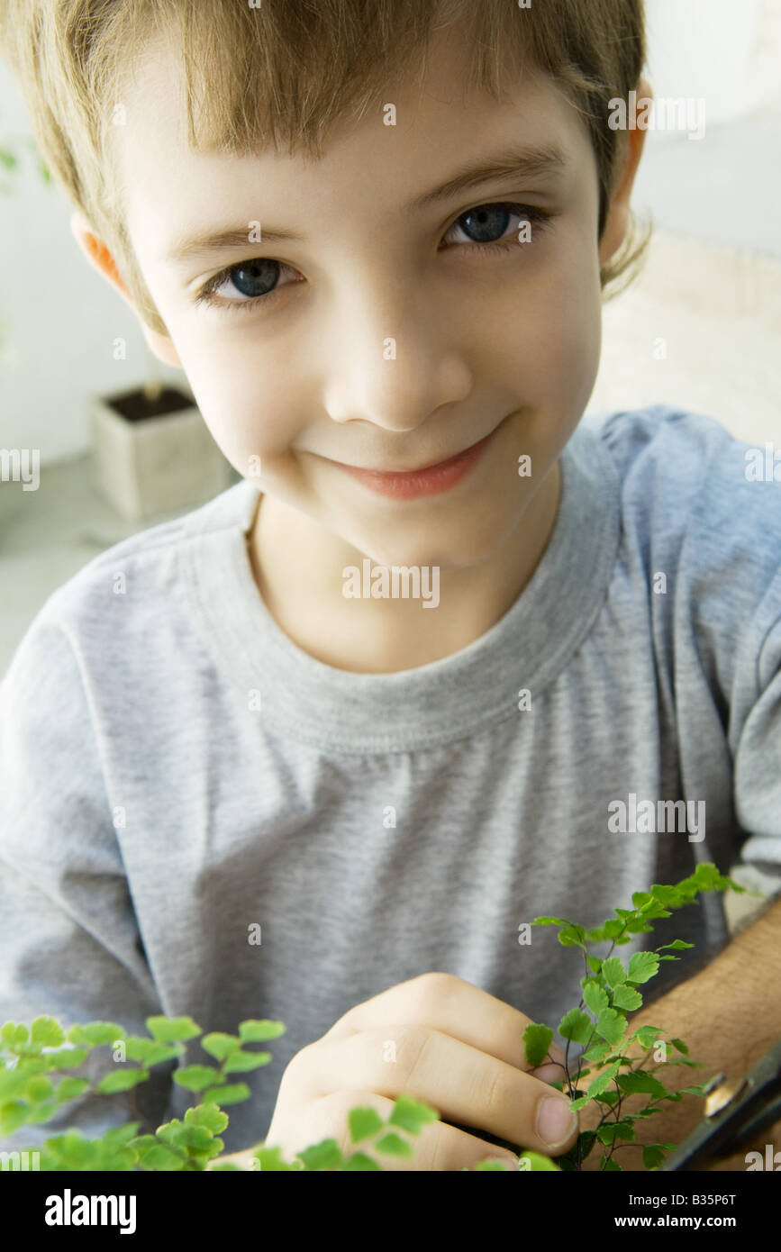 Boy touching plant, smiling at camera, close-up Stock Photo - Alamy