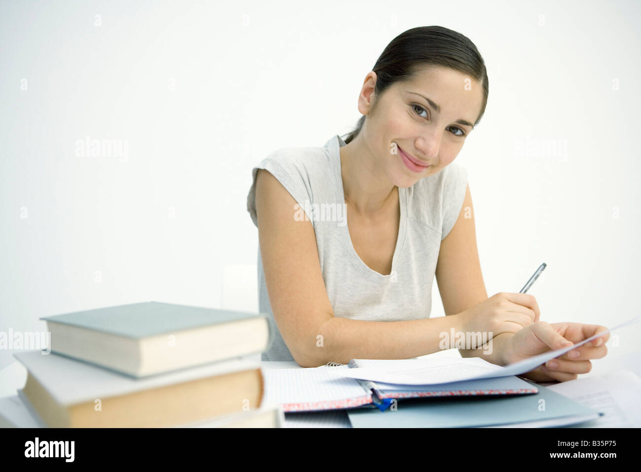 Woman working at table, holding pen and paper, smiling at camera Stock ...