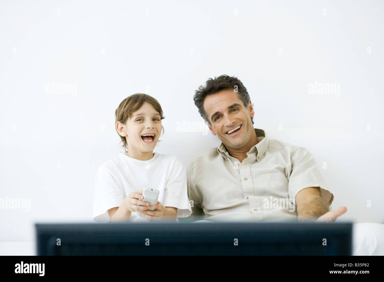 Father and son watching TV together, boy holding remote Stock Photo - Alamy