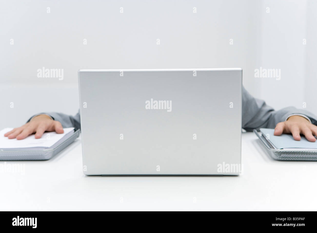 Man hiding laptop putting palms on stacks of paper to either side Stock ...
