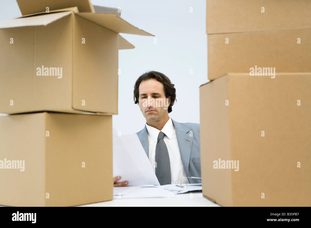 Professional man reading document, cardboard boxes piled up on both ...