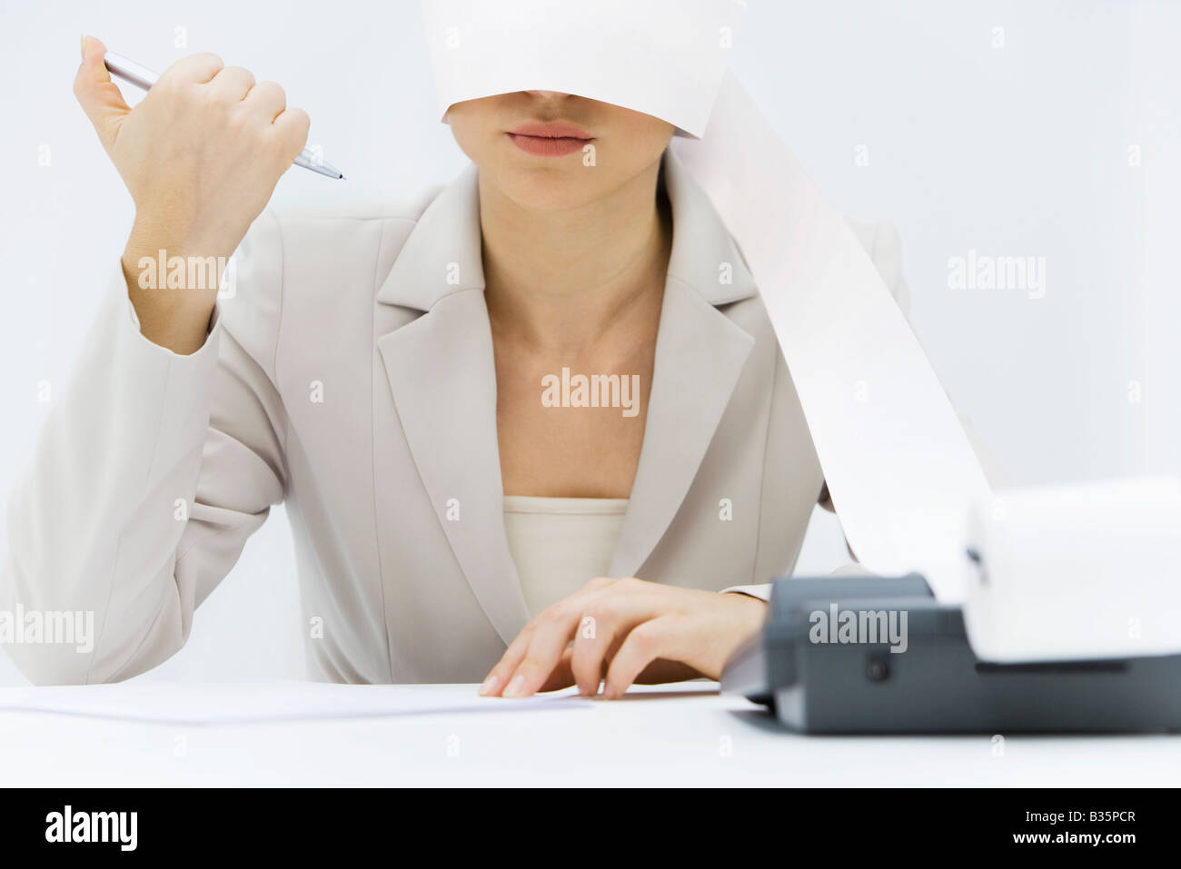 Woman sitting at desk with adding machine tape wrapped around her head ...