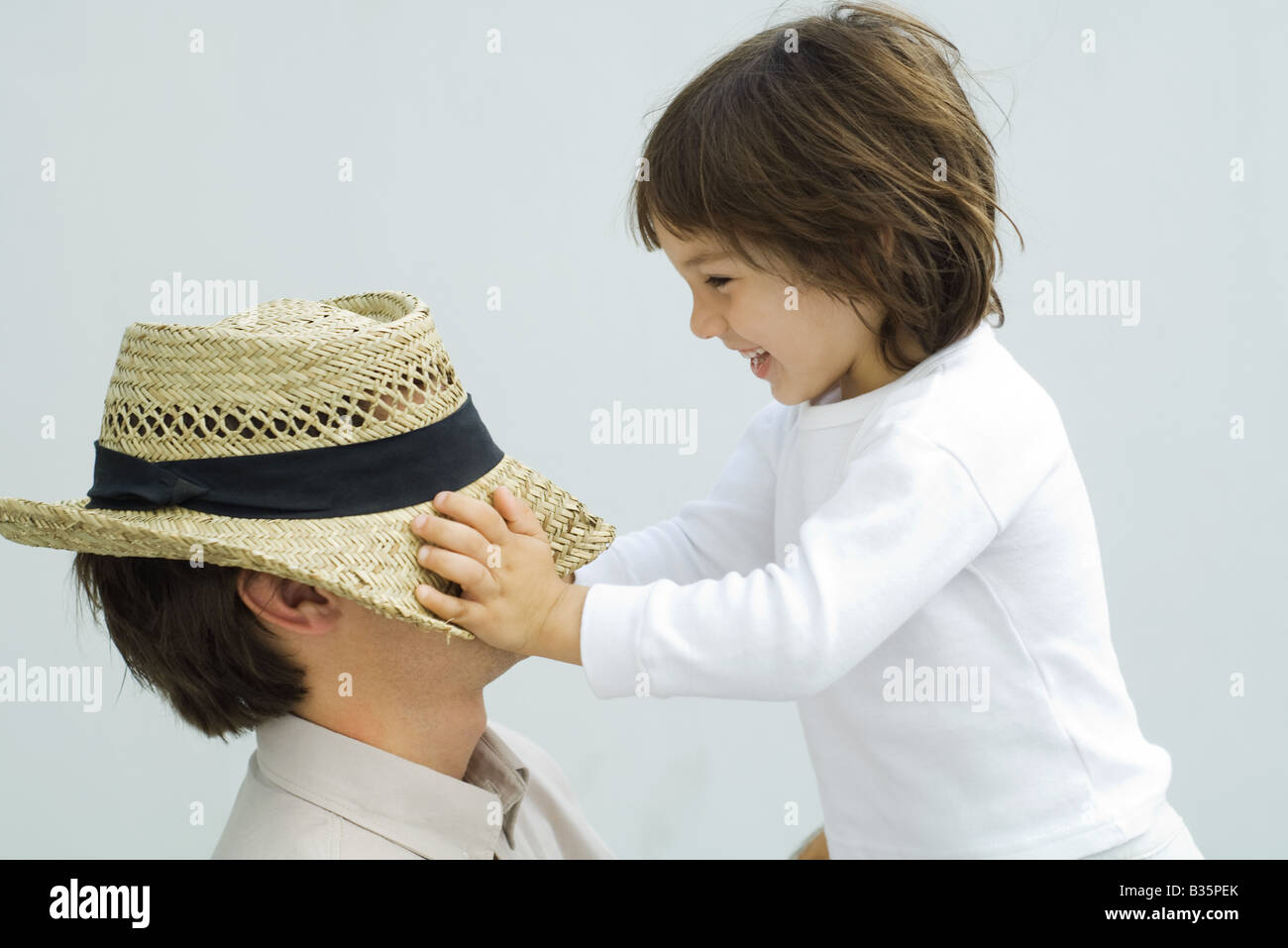 Little boy pulling hat down over his father's eyes Stock Photo - Alamy