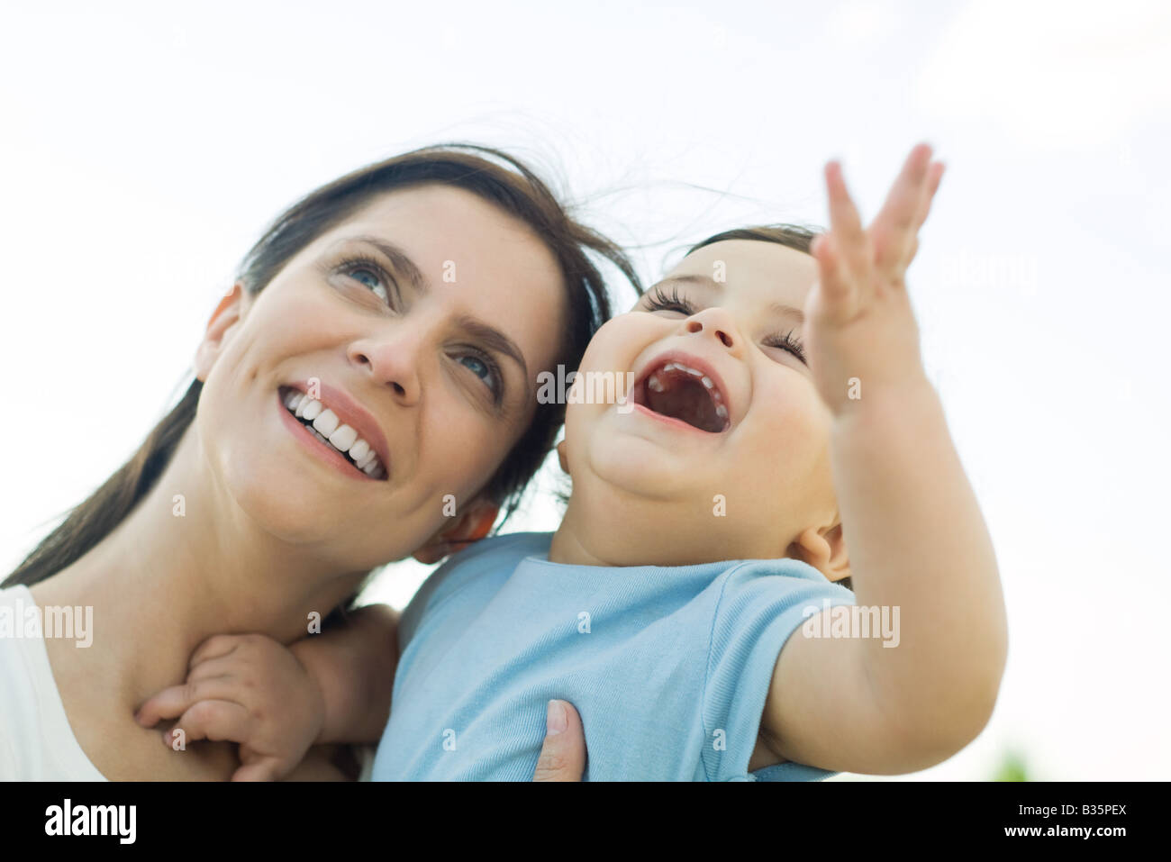 Mother holding baby, both looking up and smiling Stock Photo - Alamy