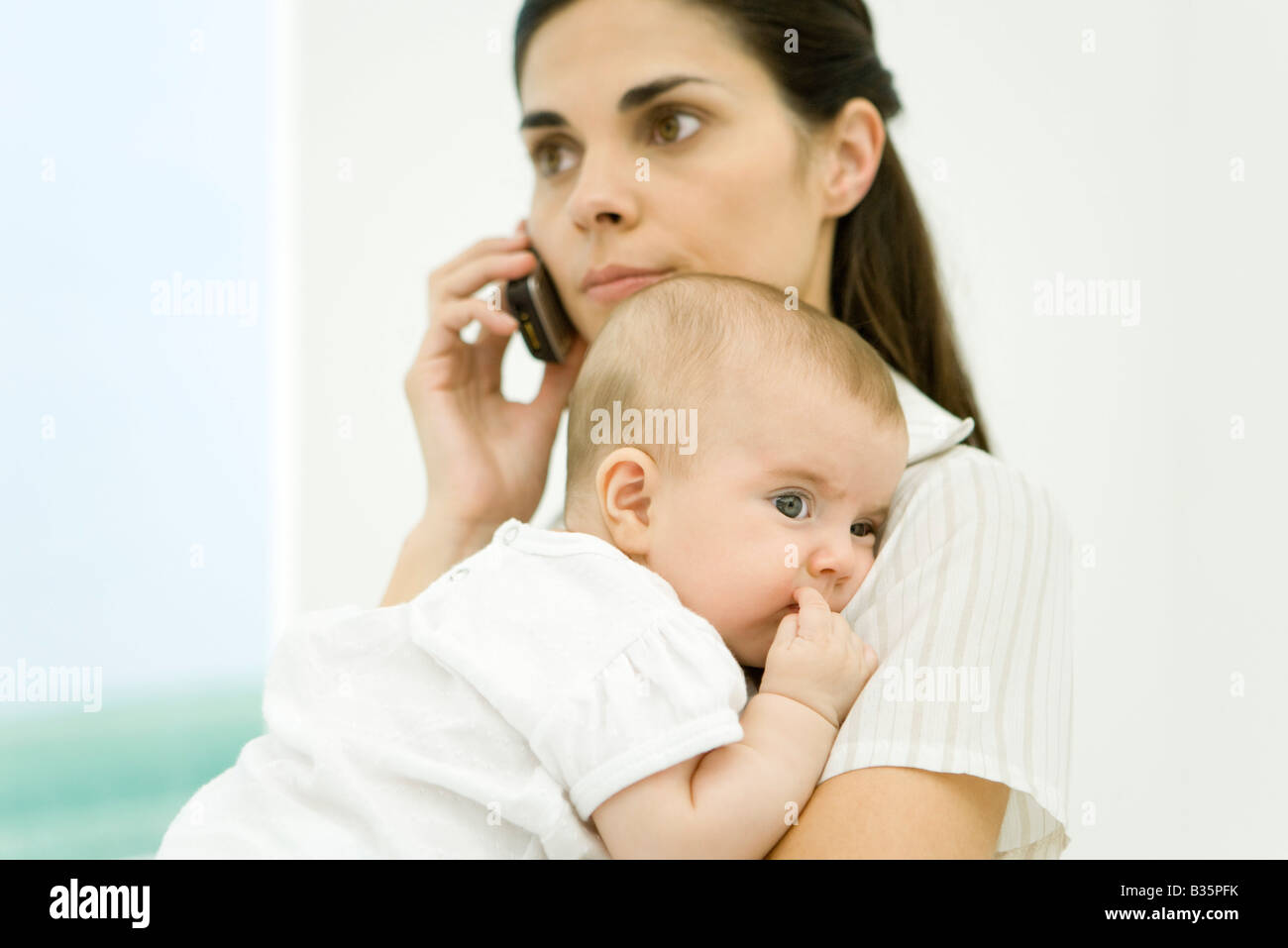 Mother holding infant, using cell phone Stock Photo - Alamy