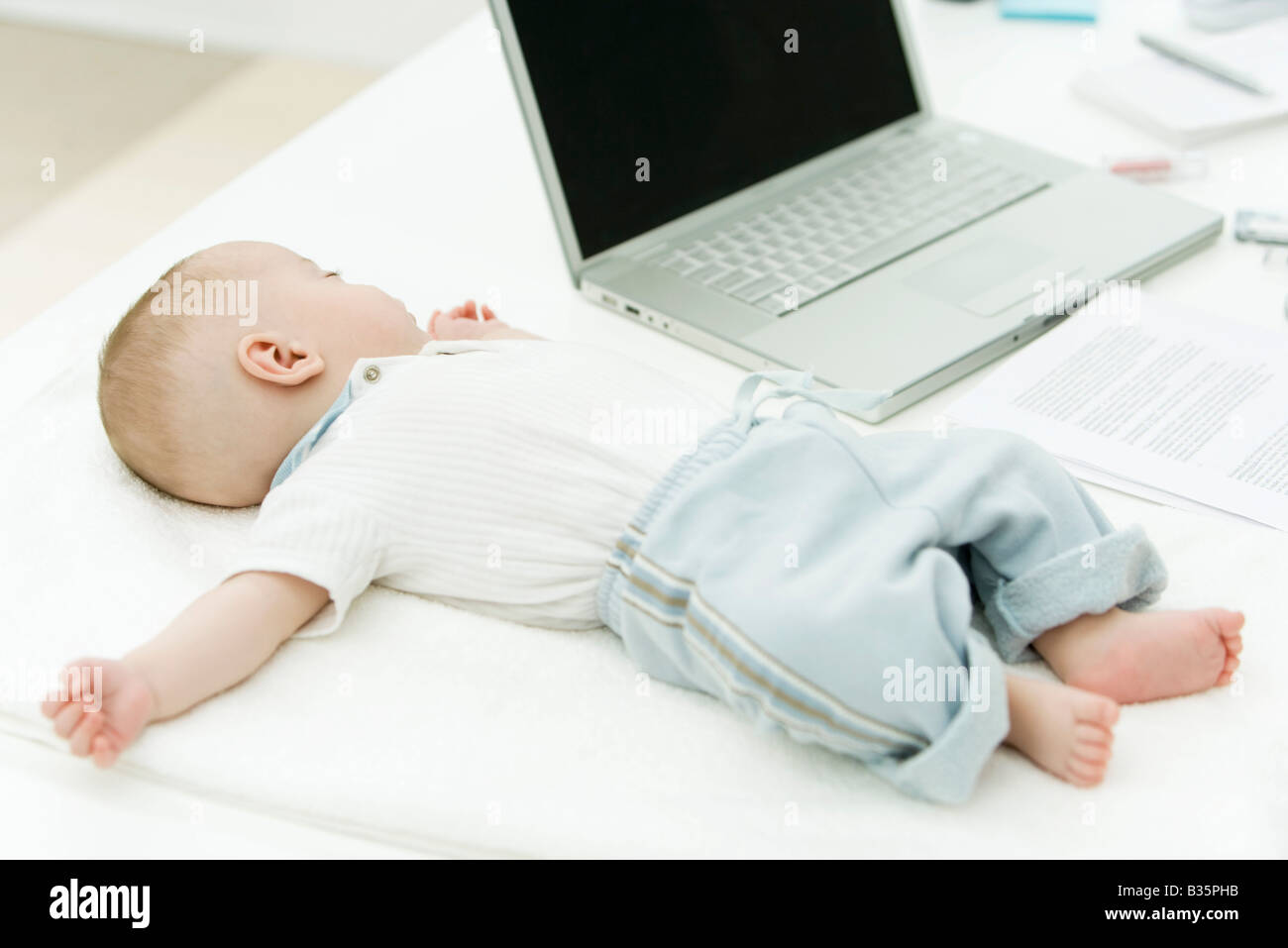 Infant sleeping on desk beside laptop computer Stock Photo - Alamy