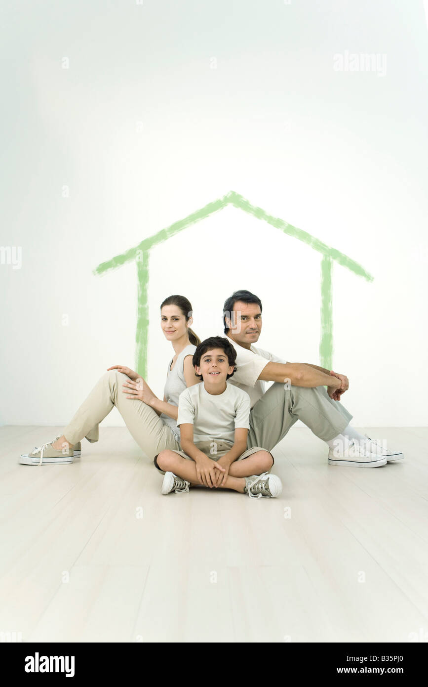 Family sitting back to back in front of outline of house painted on ...