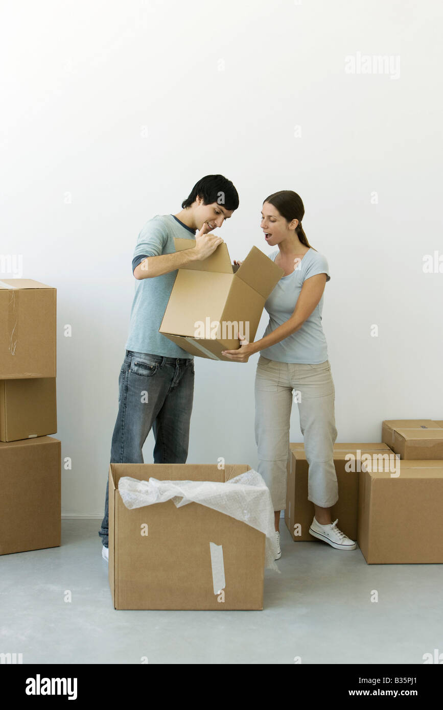Couple unpacking, man showing contents of one box, woman's mouth open ...