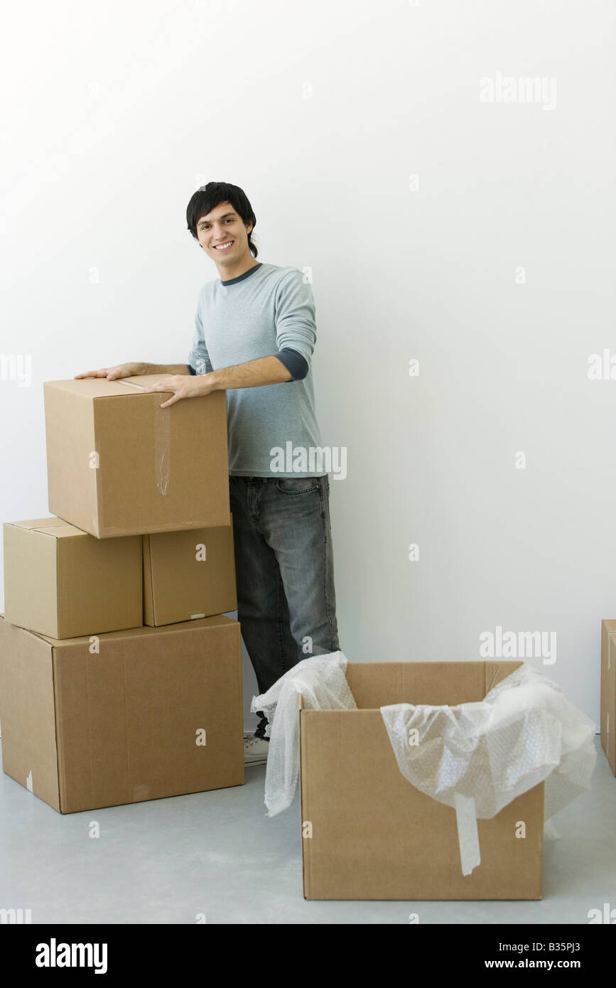 Man standing by stack of cardboard boxes, smiling at camera Stock Photo ...