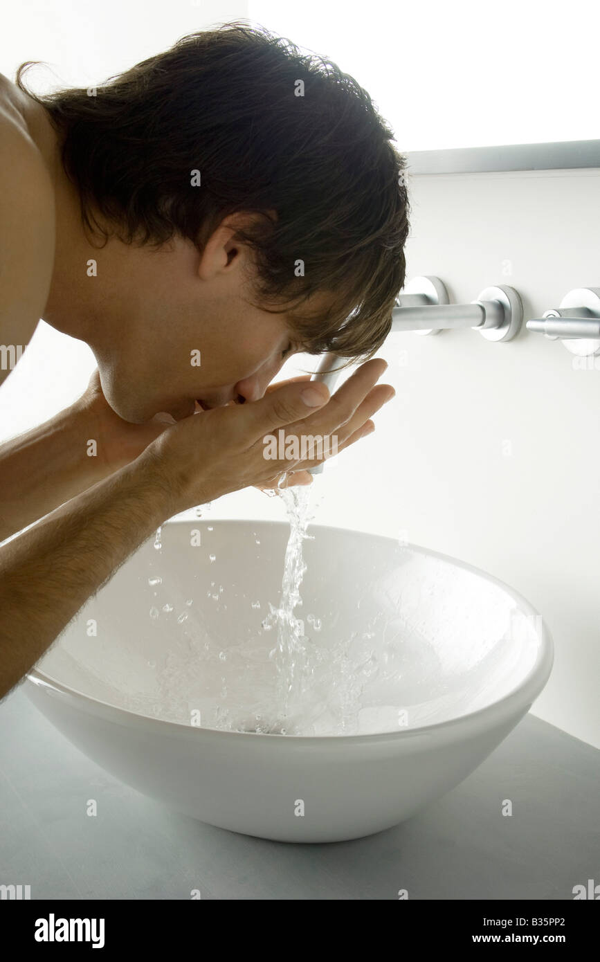 Man bending over sink, splashing water on face, side view Stock Photo ...