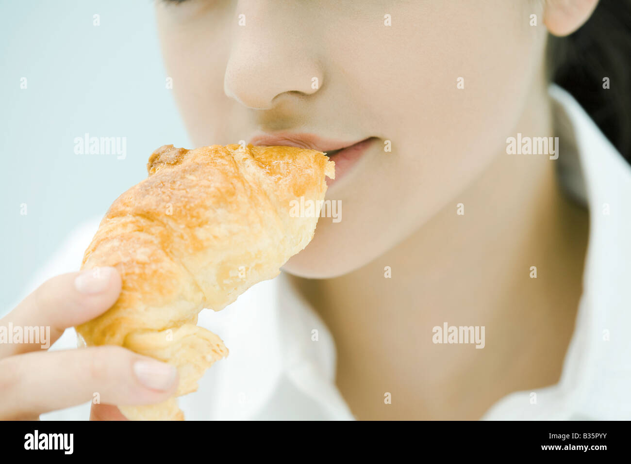 Young woman eating croissant, close-up, cropped view Stock Photo - Alamy