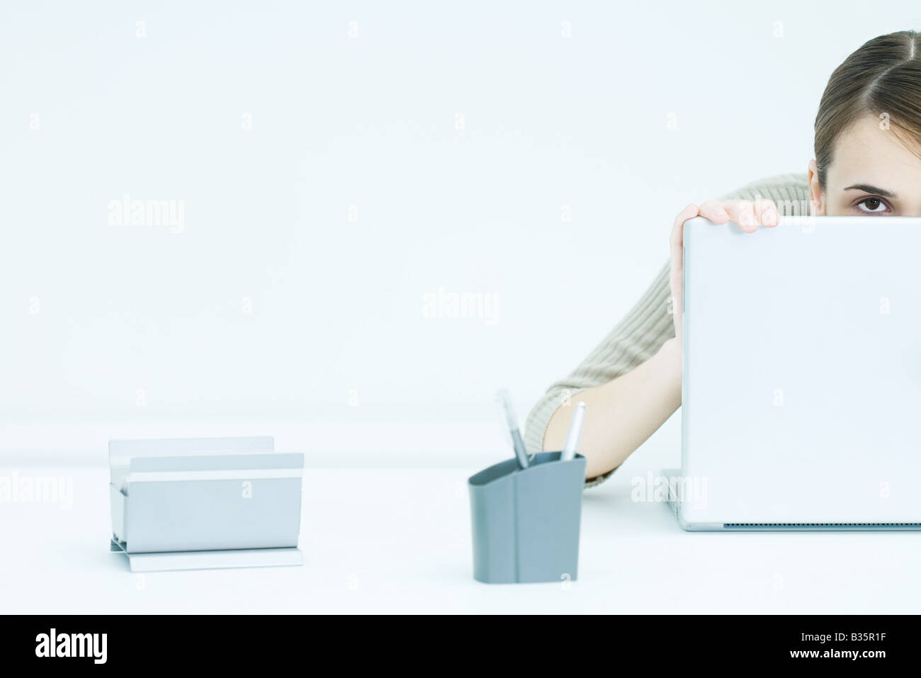 Young woman peeking over laptop, cropped view Stock Photo - Alamy