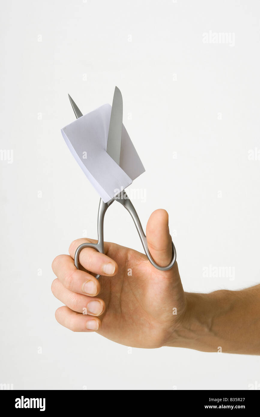 Hand using scissors to cut folded piece of paper, cropped view Stock ...