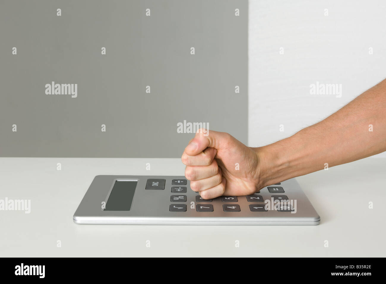 Clenched fist hitting oversized calculator, cropped view Stock Photo ...