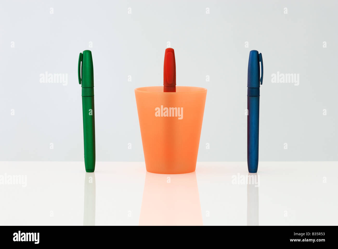 Pens standing upright in a row, the middle pen upside down inside of ...