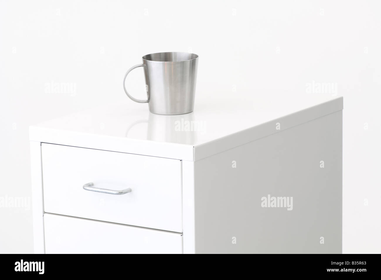 Metal cup on top of a filing cabinet Stock Photo - Alamy