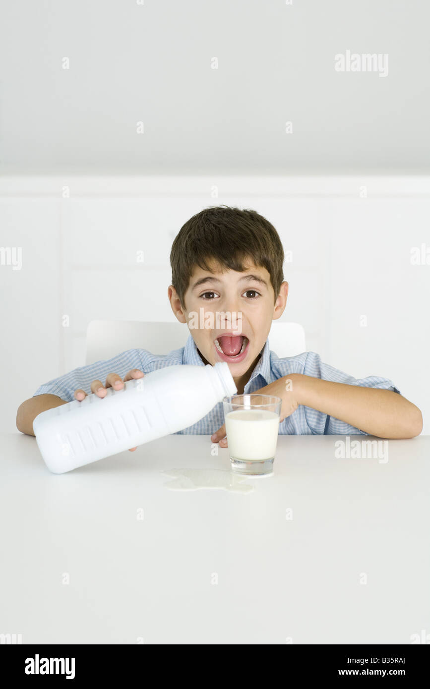 Boy pouring milk into glass, mouth open, spilled milk on table Stock ...