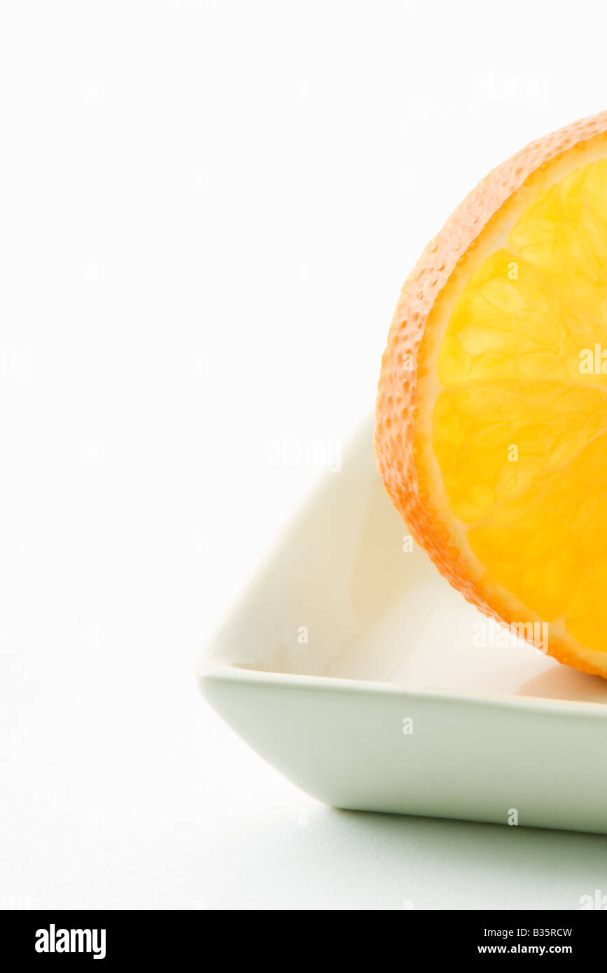 Orange slice in small dish, close-up Stock Photo - Alamy
